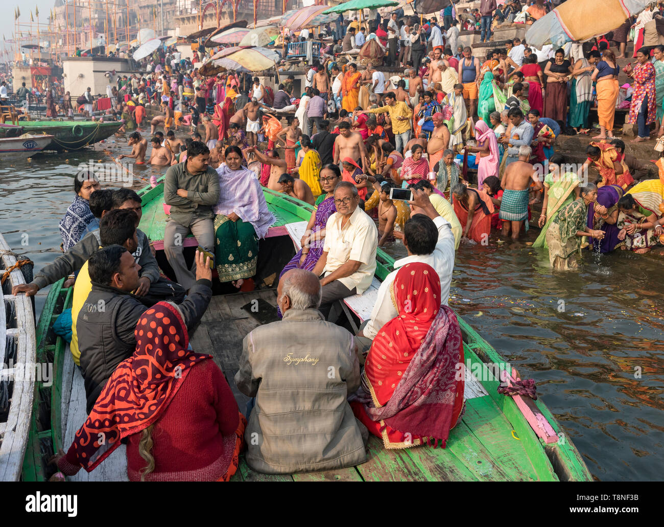 Tourists in a boat wath worshippers performing ritual bath and prayers ...