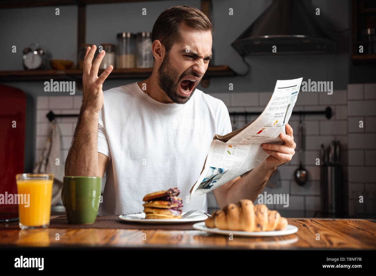 Angry shocked man having breakfast, reading newspaper Stock Photo - Alamy