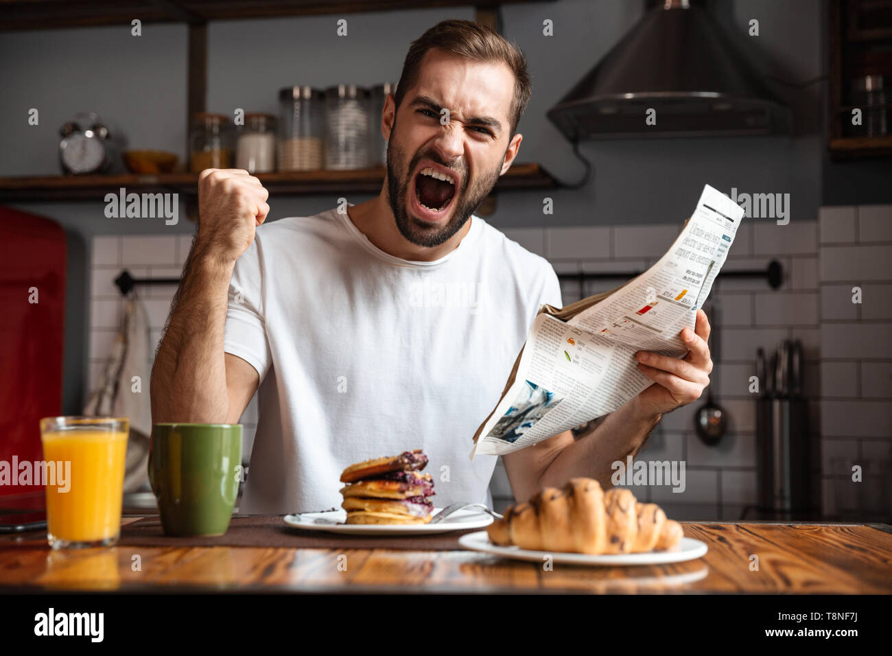 Angry shocked man having breakfast, reading newspaper Stock Photo - Alamy