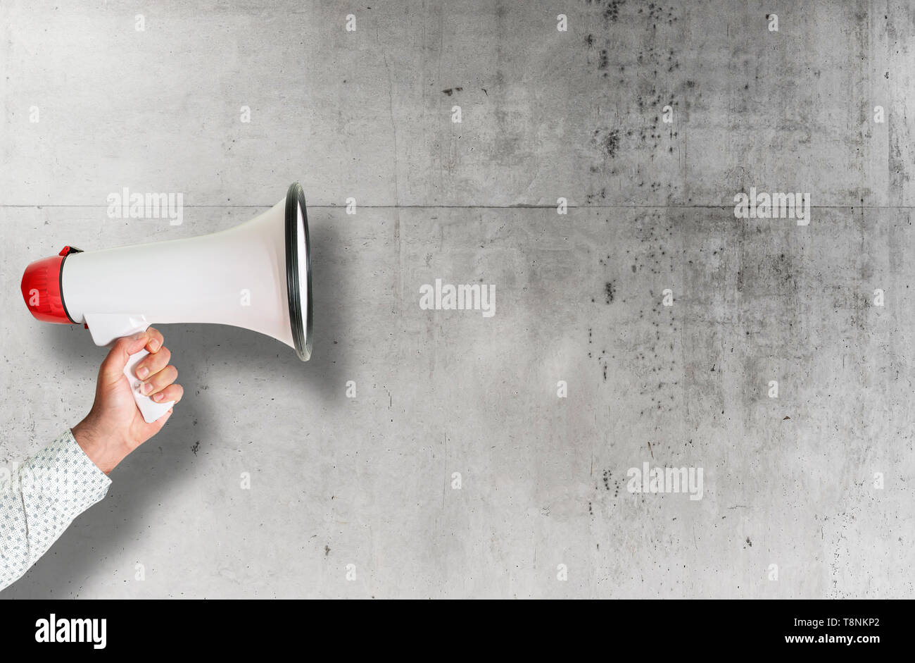 hand holding red and white megaphone against rough concrete wall Stock ...