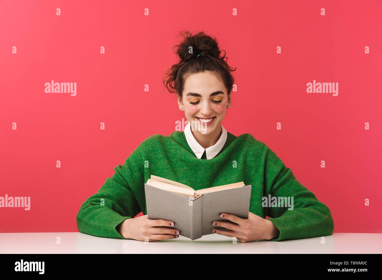 Beautiful young nerd student girl sitting at the table isolated over ...