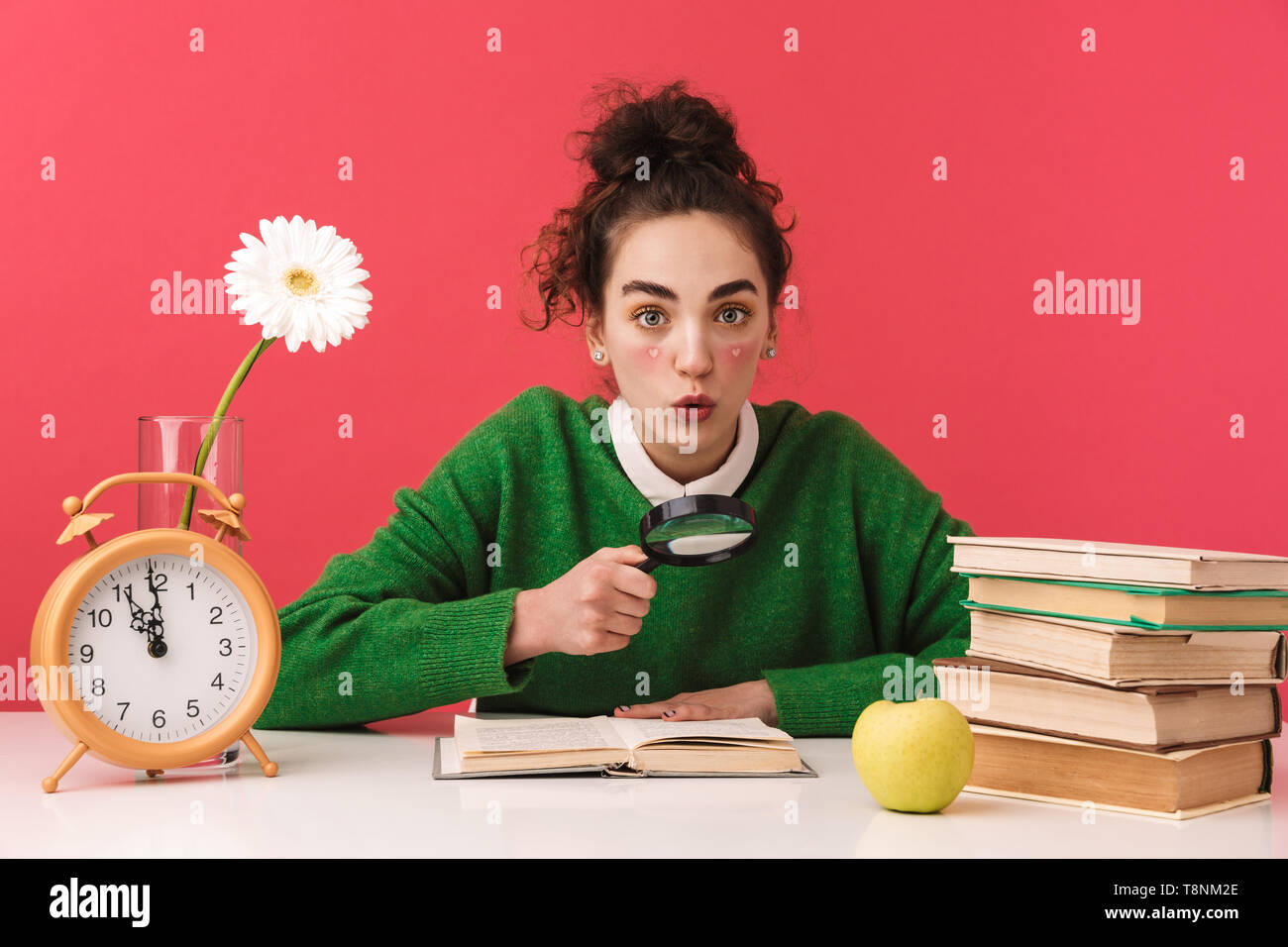 Beautiful young nerd student girl sitting at the table isolated over ...