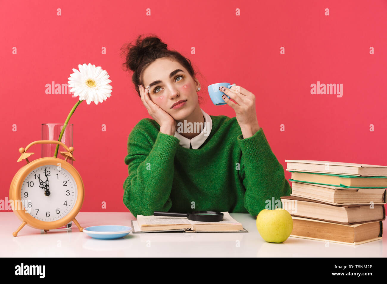 Beautiful young nerd student girl sitting at the table isolated over ...
