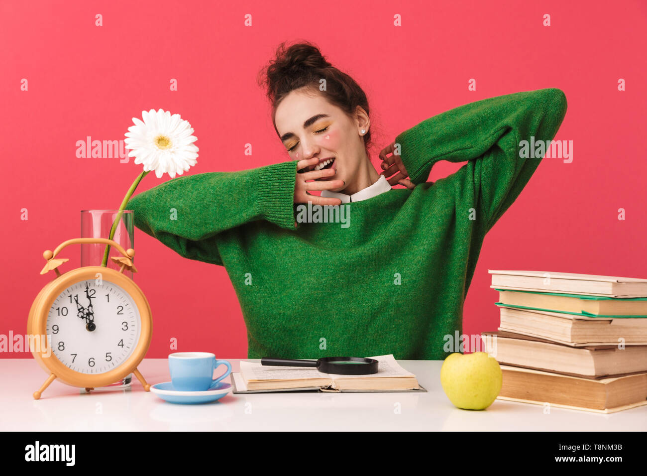 Beautiful young nerd student girl sitting at the table isolated over ...