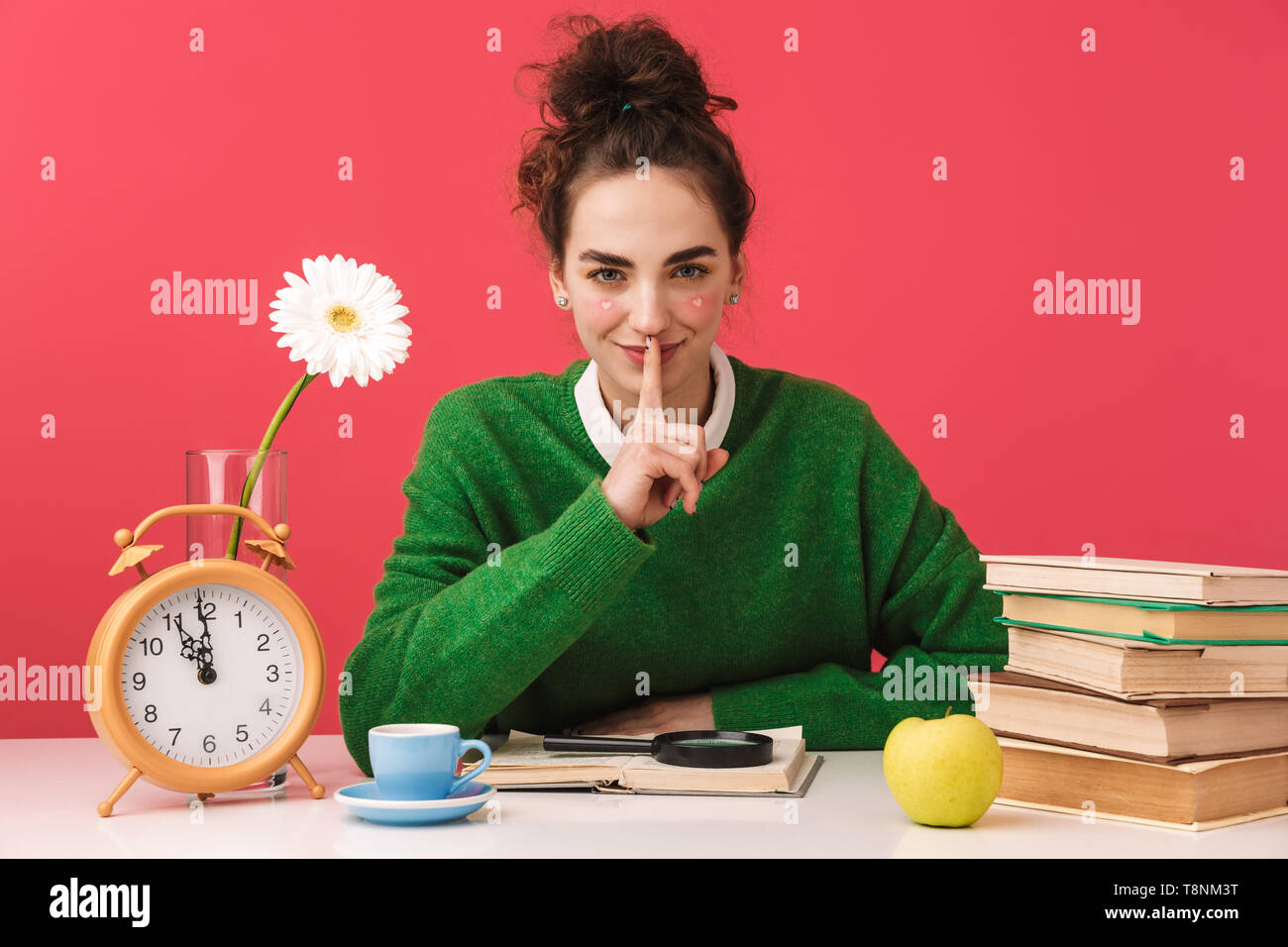 Beautiful young nerd student girl sitting at the table isolated over ...