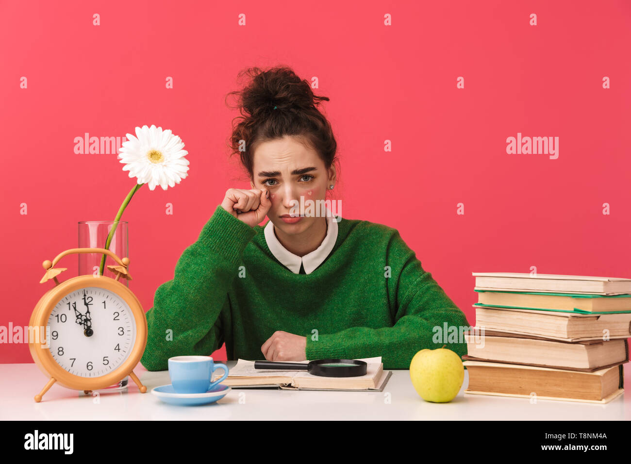 Beautiful young nerd student girl sitting at the table isolated over ...