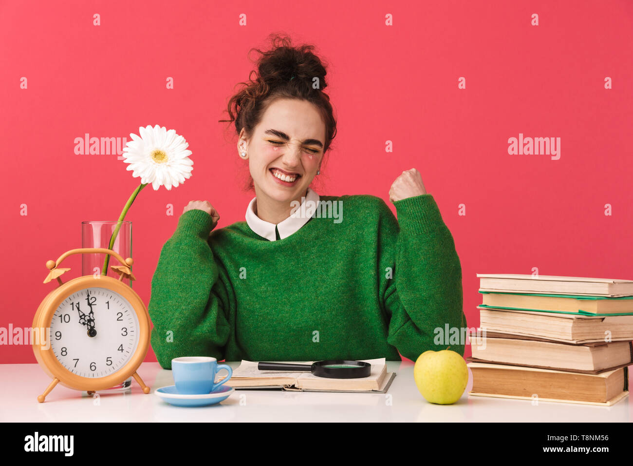 Beautiful young nerd student girl sitting at the table isolated over ...
