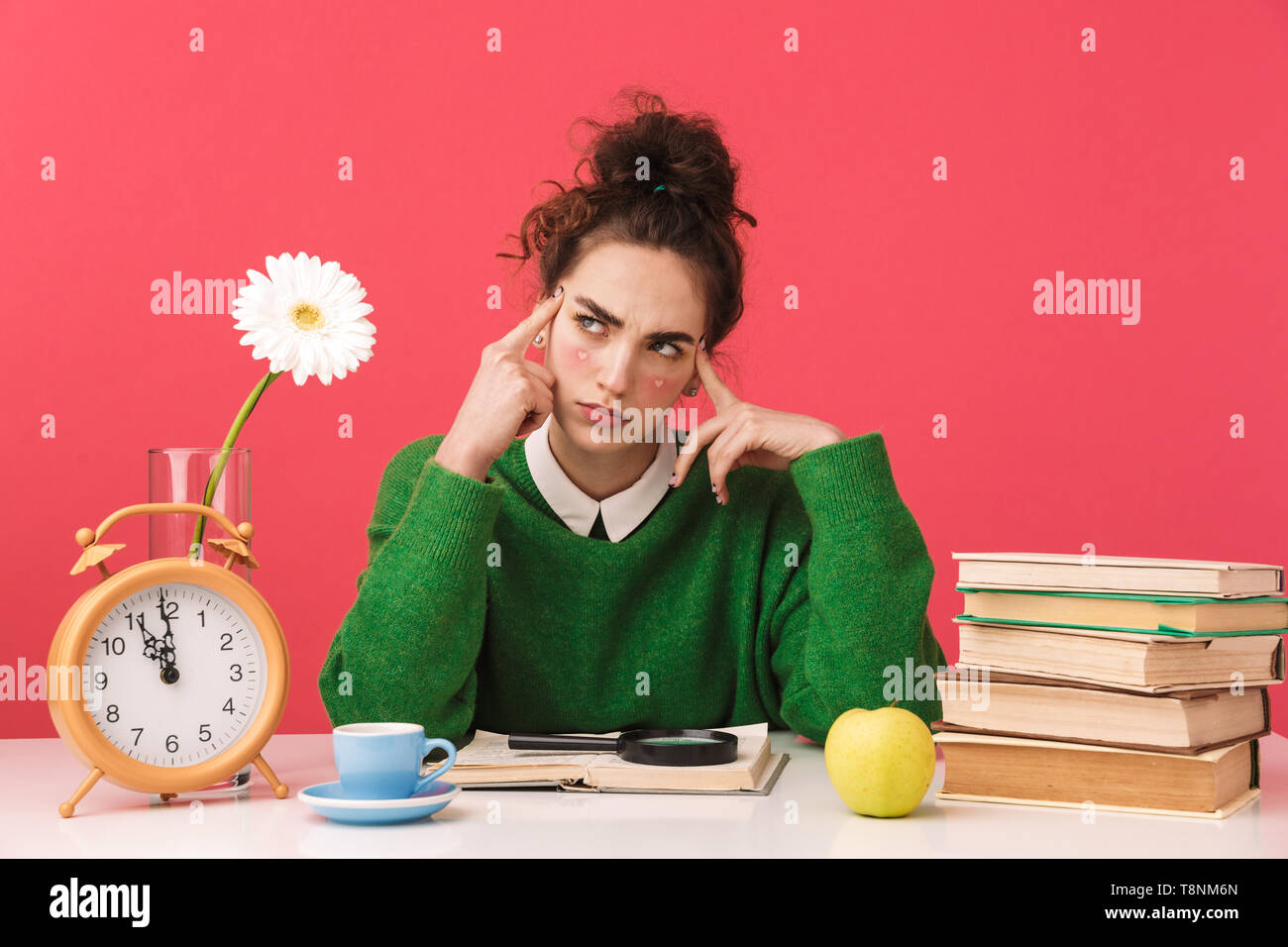 Beautiful young nerd student girl sitting at the table isolated over ...