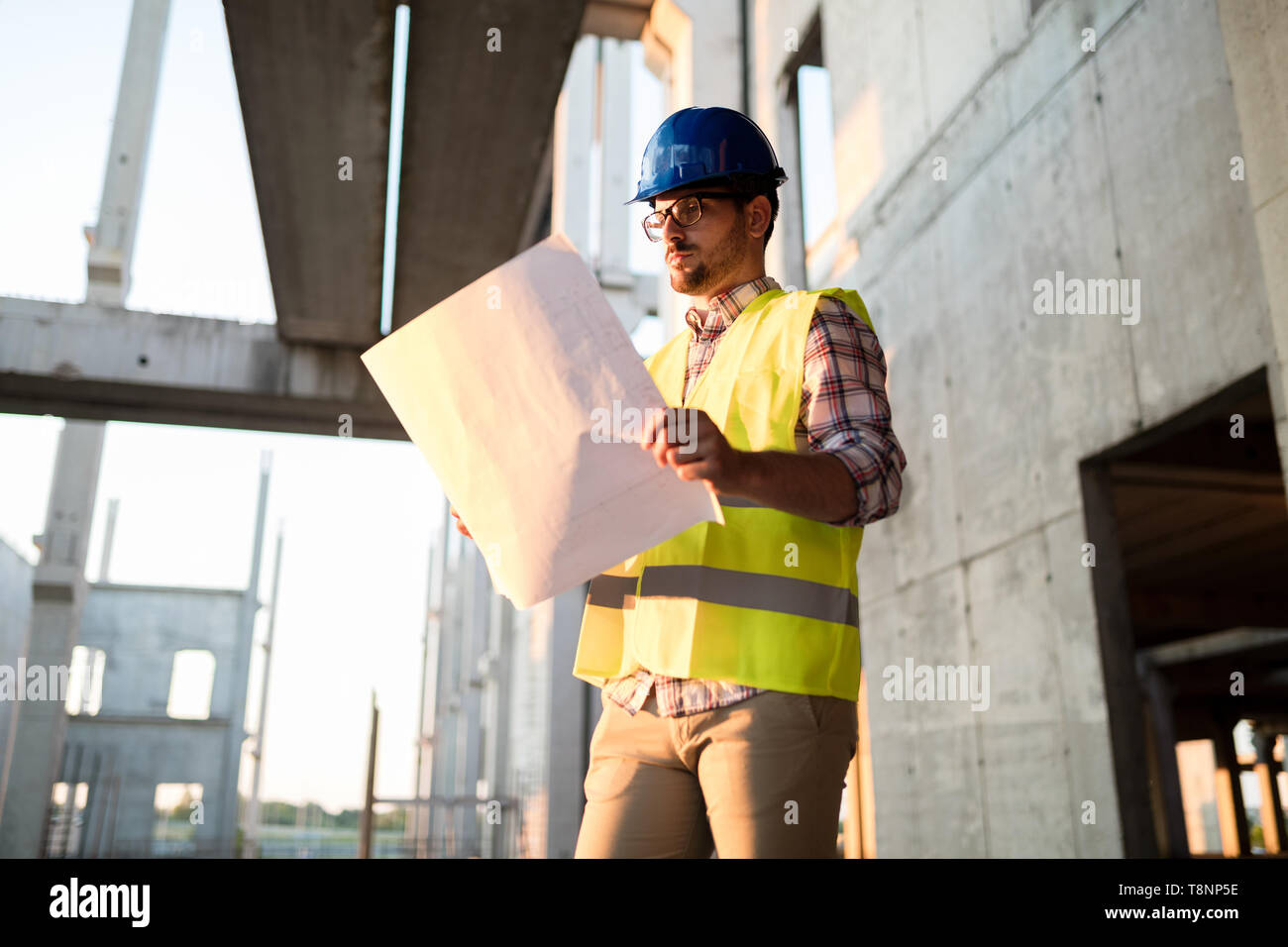 Engineer working on construction site and holding blueprint Stock Photo ...