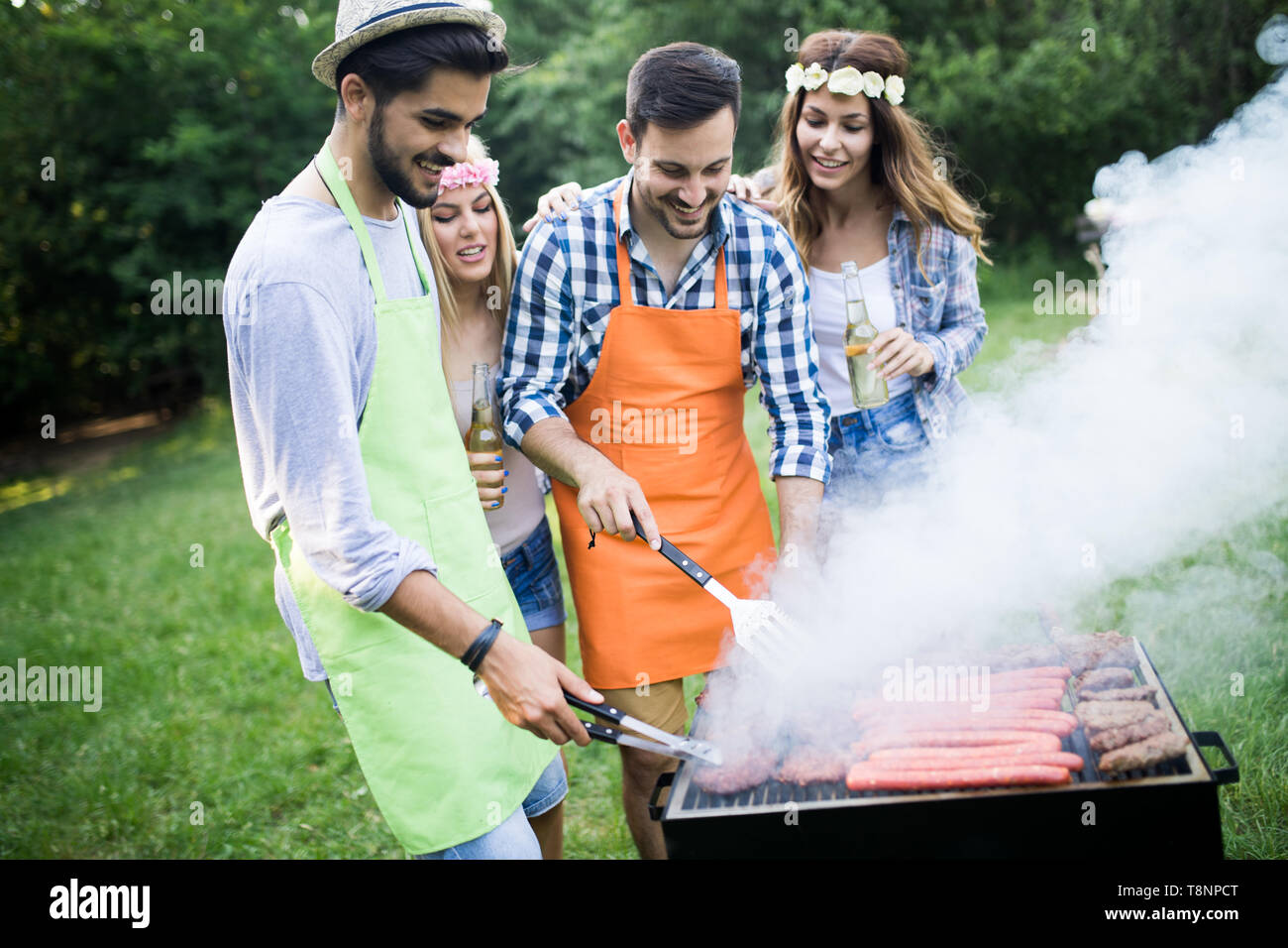 Happy group of friends making a barbecue together outdoors in the ...