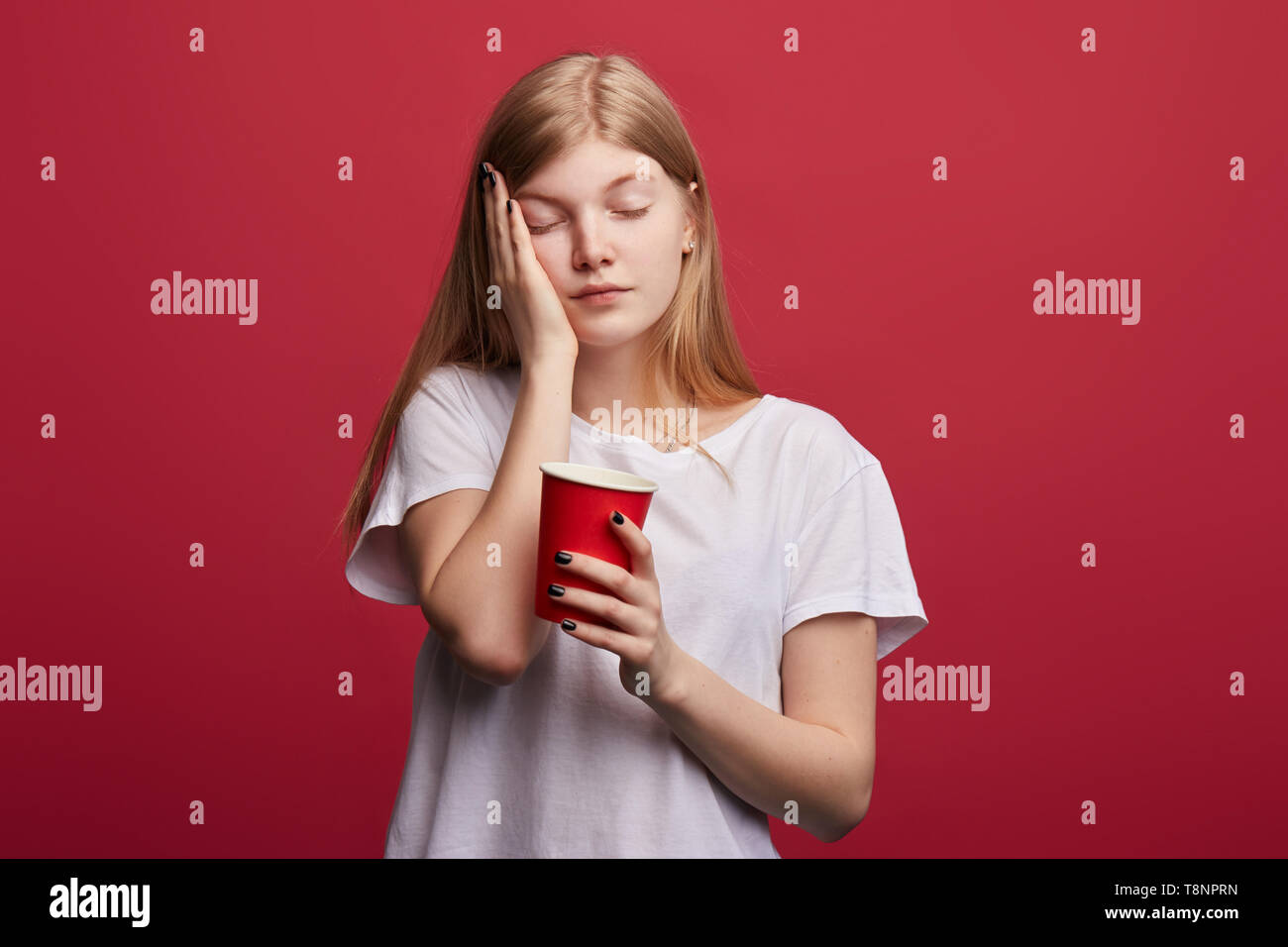 tired sleepy beautiful woman with closed eyes covers her cheek with ...