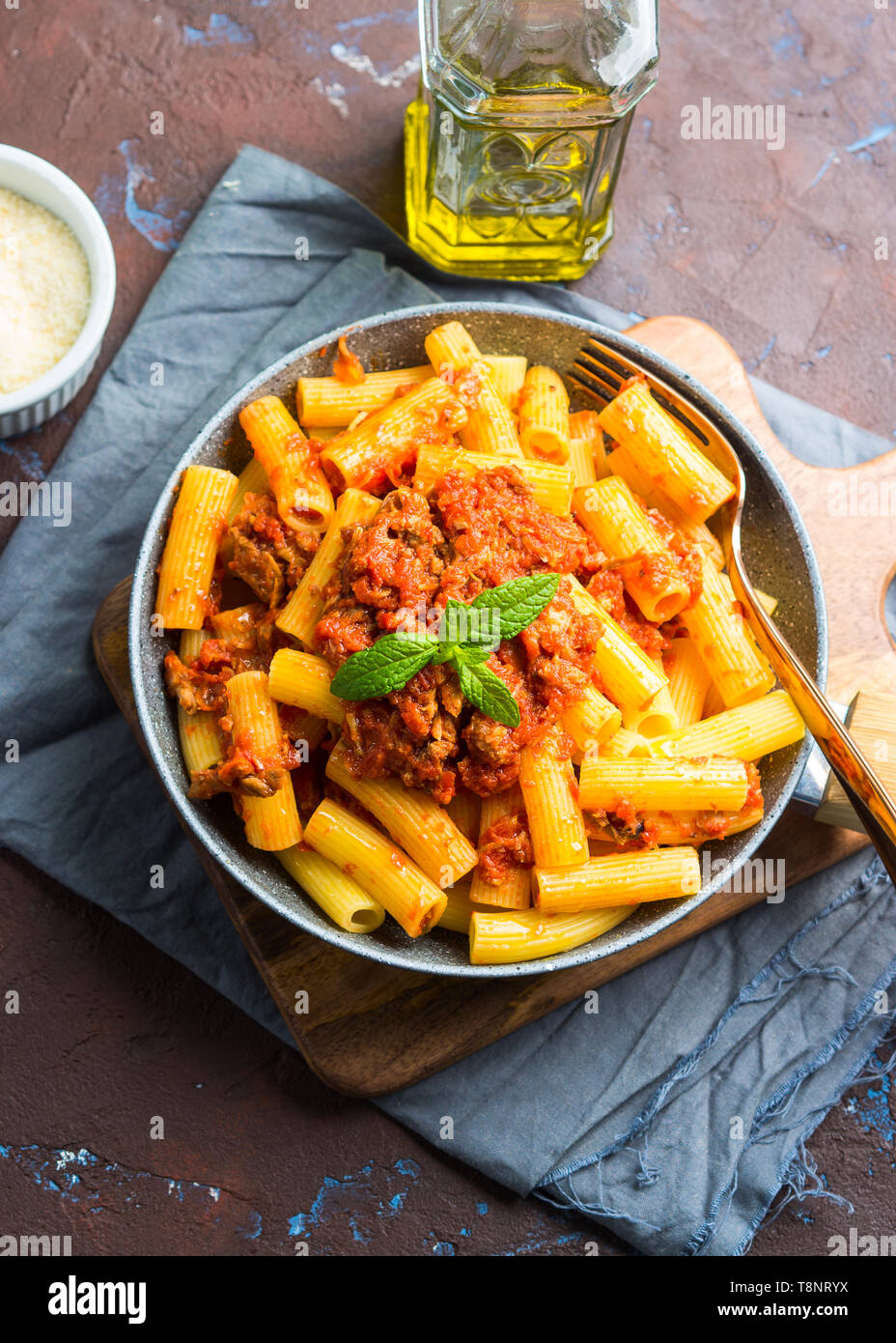 Delicious rigatoni pasta with italian tomato meat ragu sauce served in a pan on dark brown ...