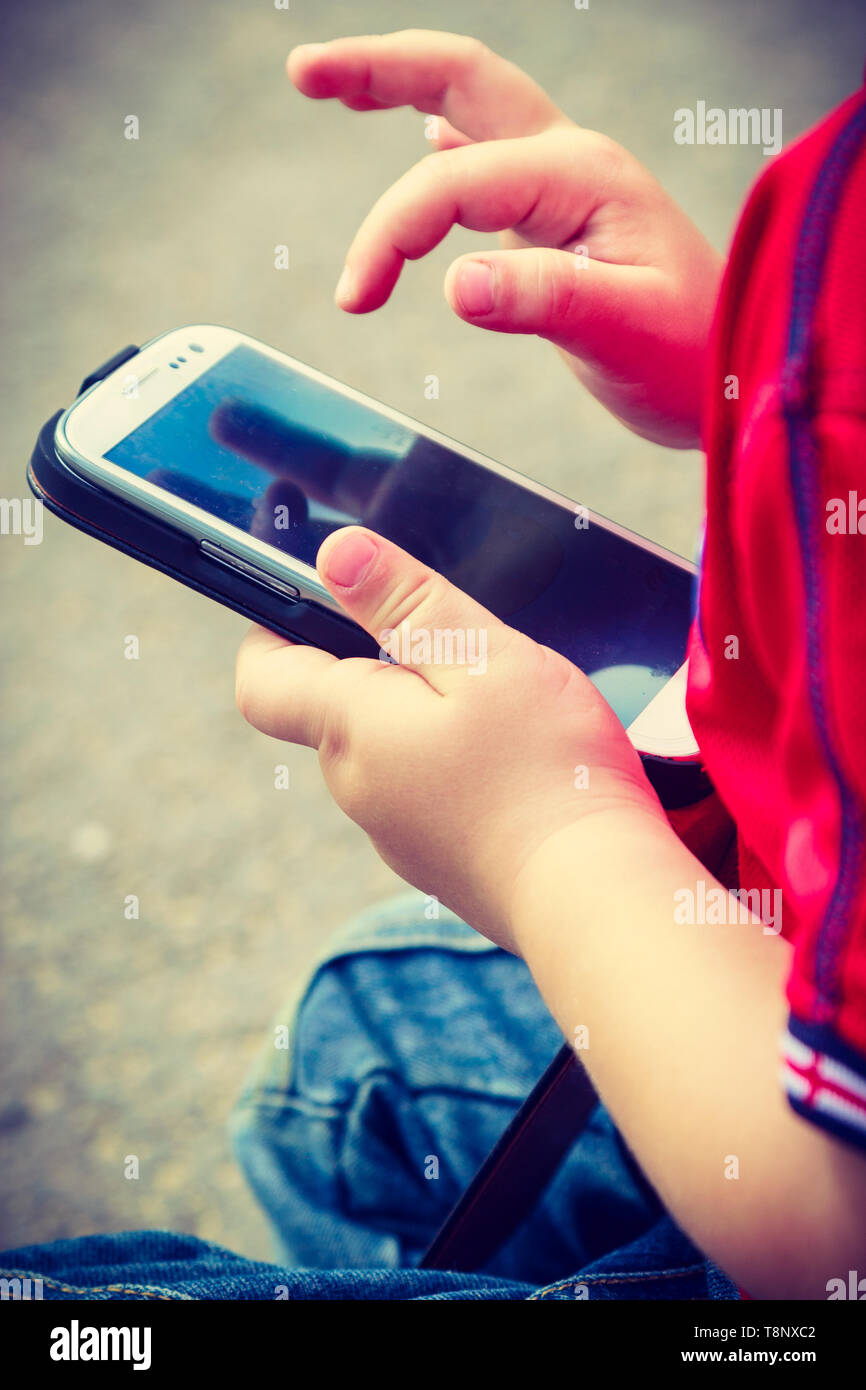 Little boy child kid playing games on smartphone mobile phone outdoor ...