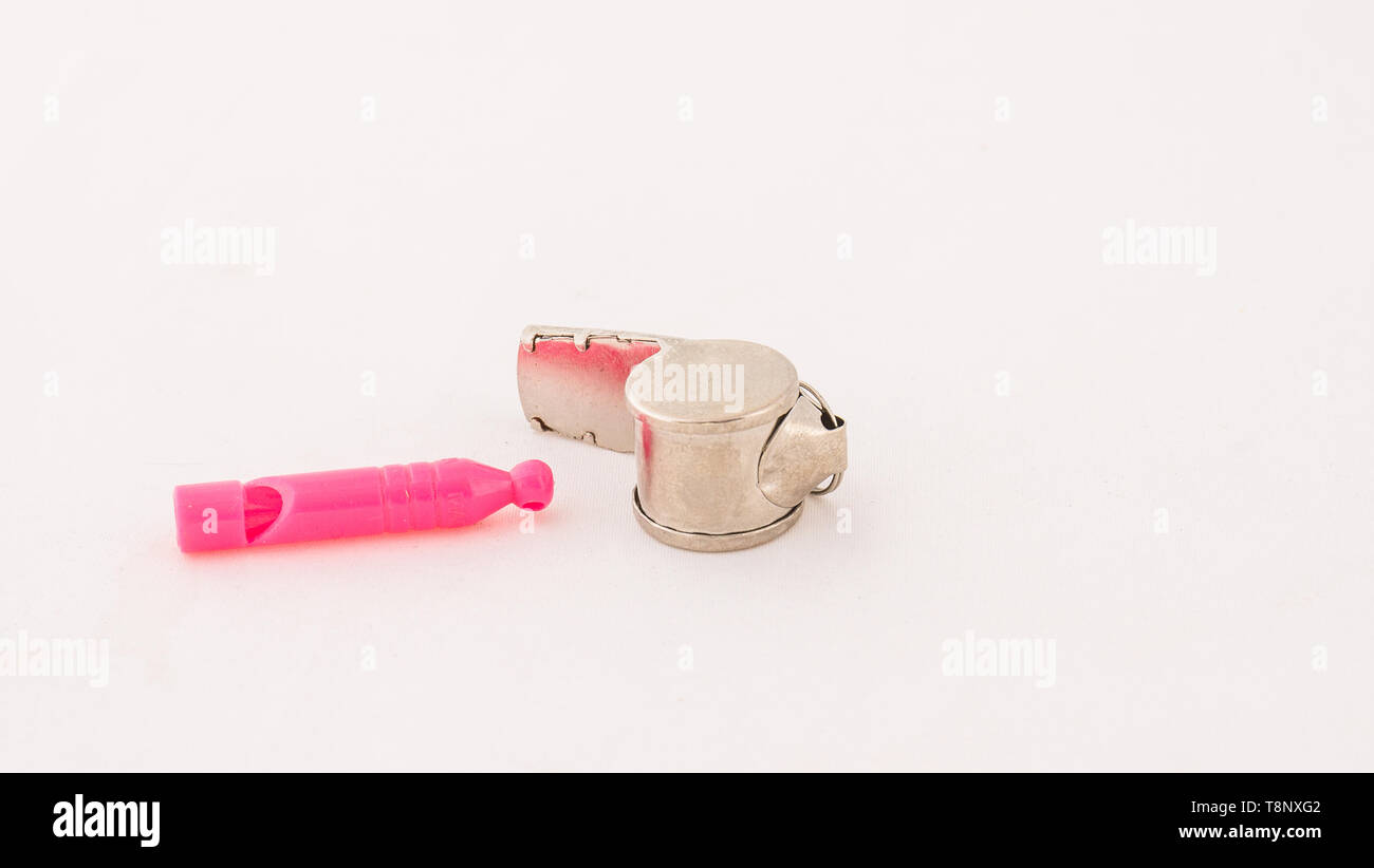 A pink whistle and a sliver whistle isolated on a white background ...