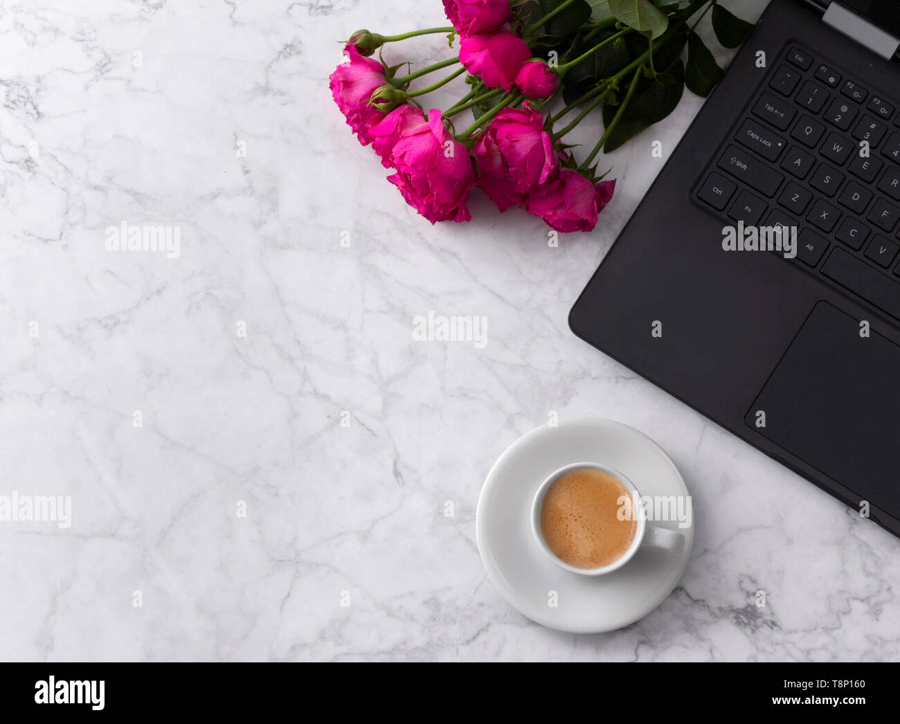 Feminine workspace with laptop computer, bouquet of roses and coffee on ...