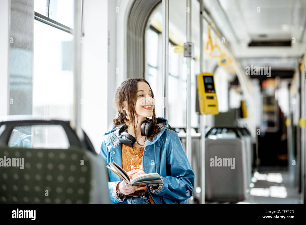 Young woman reading book while moving in the modern tram, happy ...