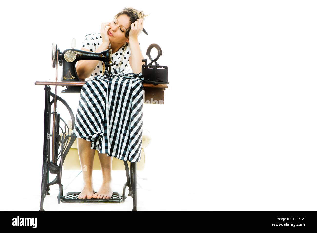 Tired overworked woman dressmaker sleeping by old sewing manual machine ...
