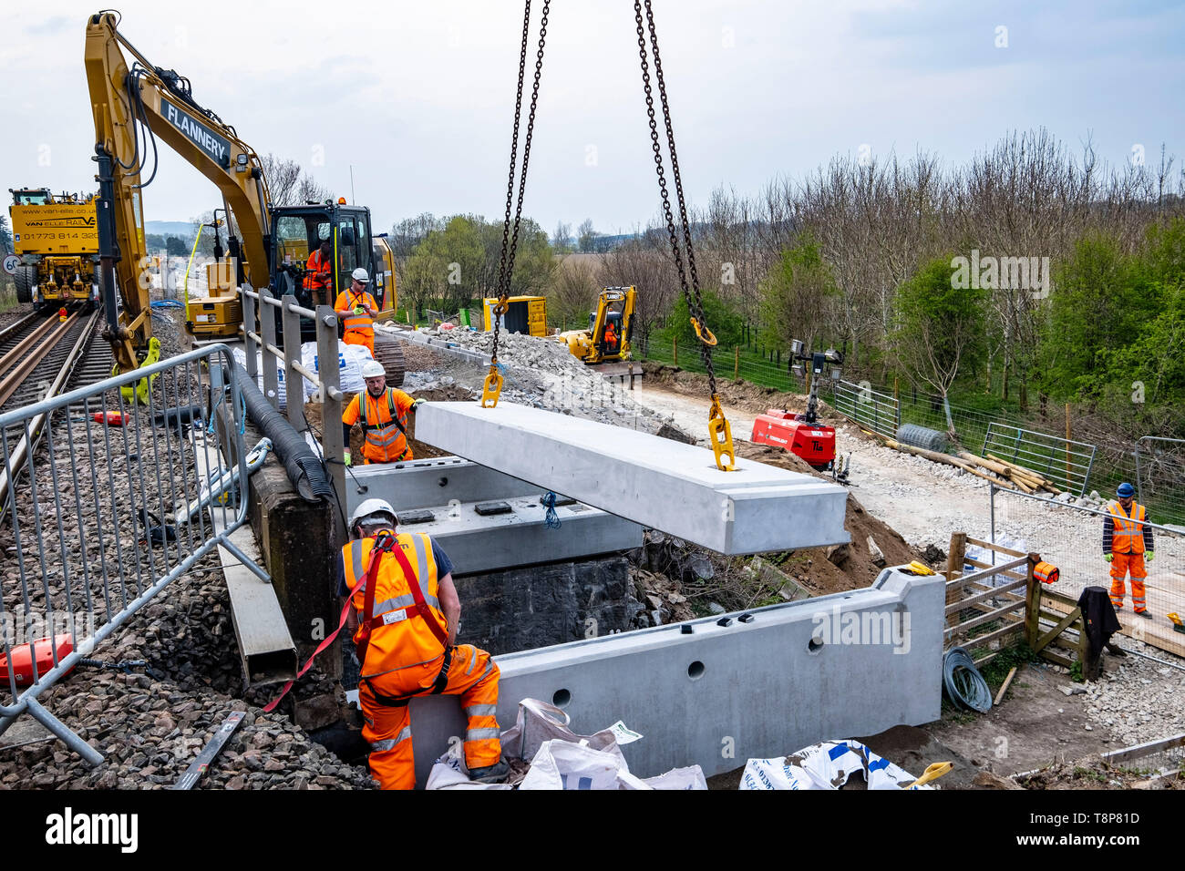 Railway workers constructing railway and lifting rail bridge into place ...