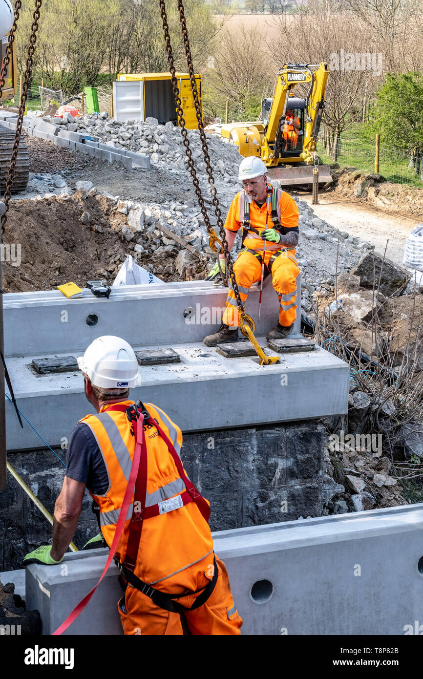 Railway workers constructing railway and lifting rail bridge into place ...