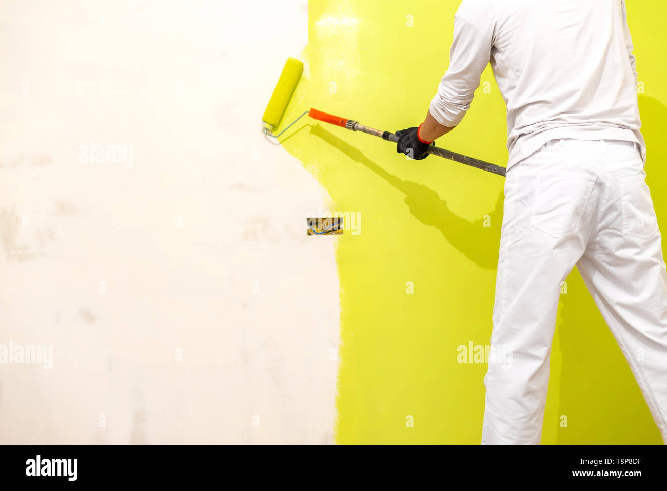 Painter use paint roller on new restored wall. Painter painting house ...