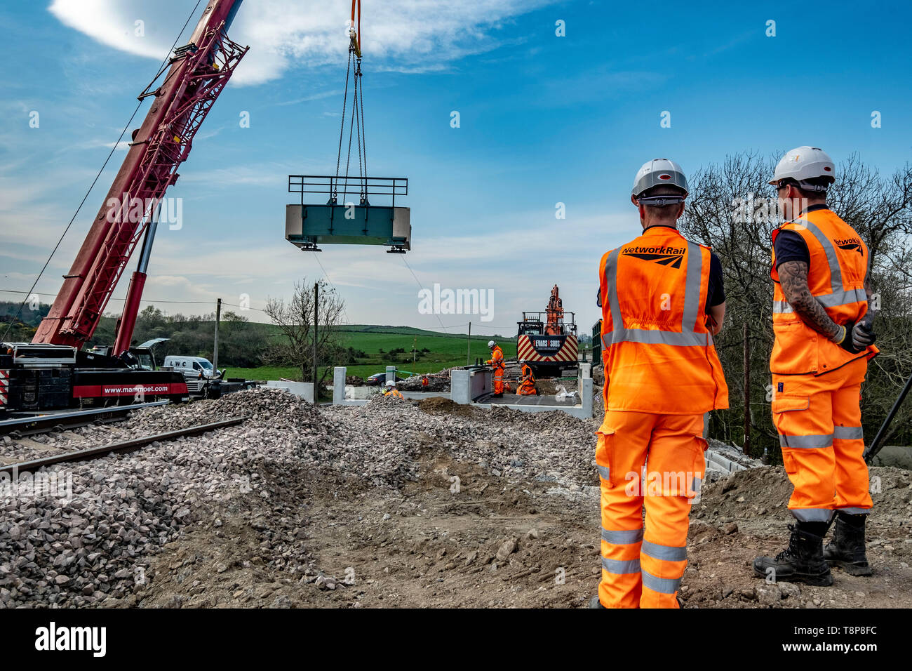 Railway workers constructing railway and lifting rail bridge into place ...