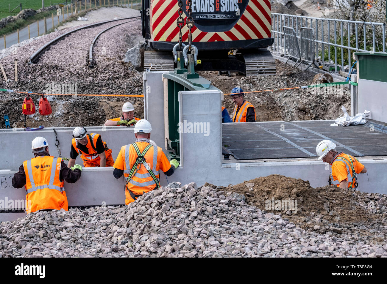 Railway workers constructing railway and lifting rail bridge into place ...