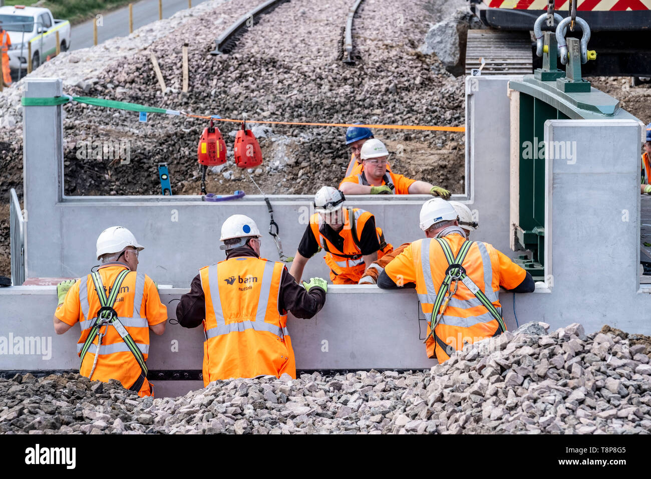 Railway workers constructing railway and lifting rail bridge into place ...
