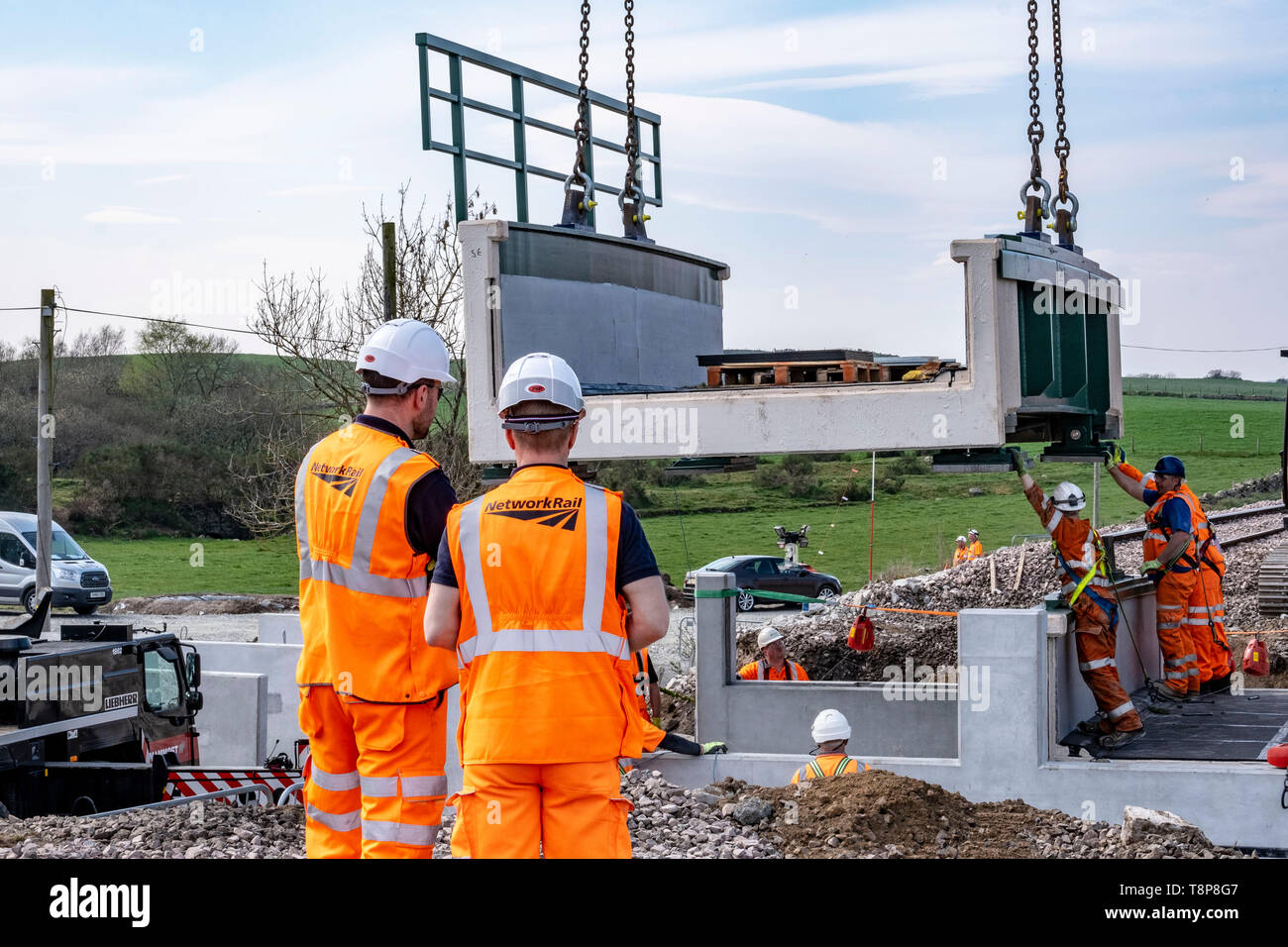 Railway workers constructing railway and lifting rail bridge into place ...