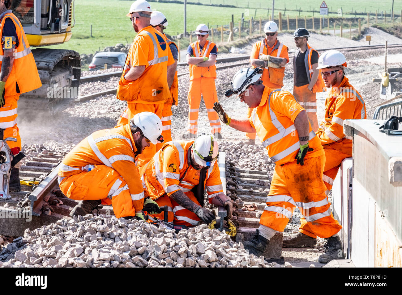 Railway workers constructing railway and lifting rail bridge into place ...