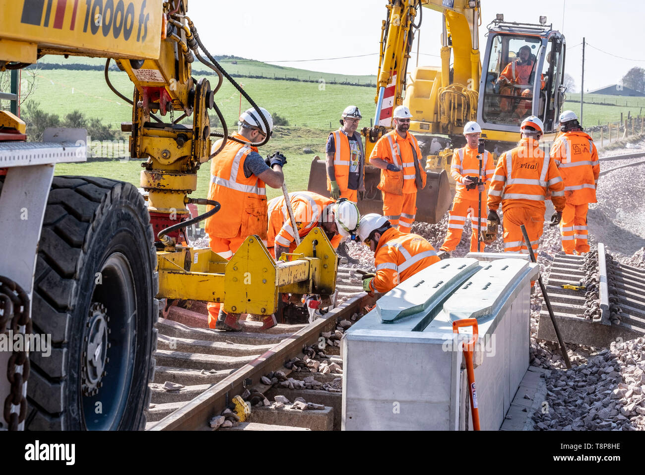 Railway workers constructing railway and lifting rail bridge into place ...