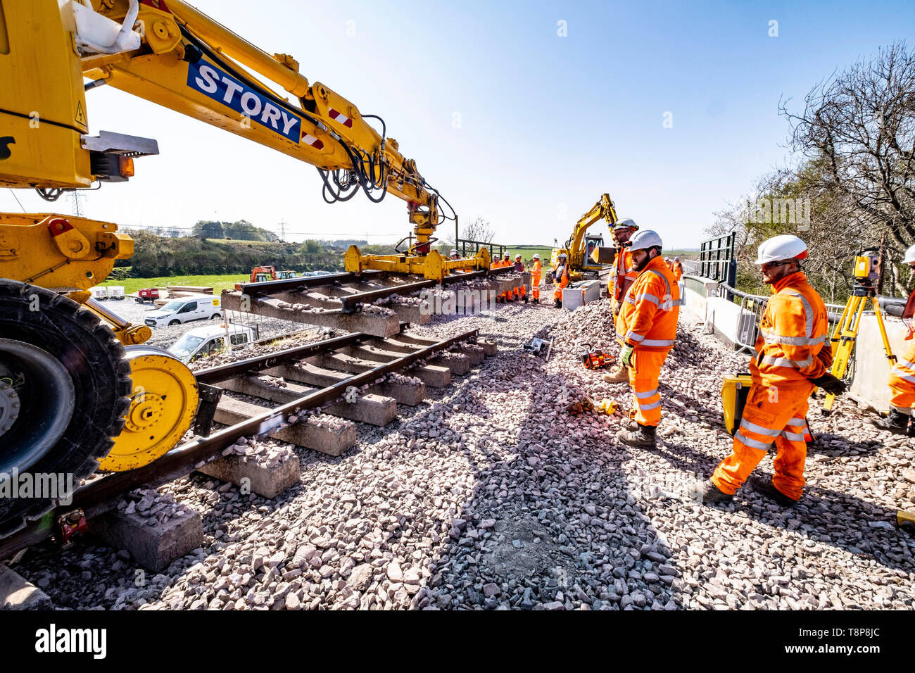 Railway workers constructing railway and lifting rail bridge into place ...