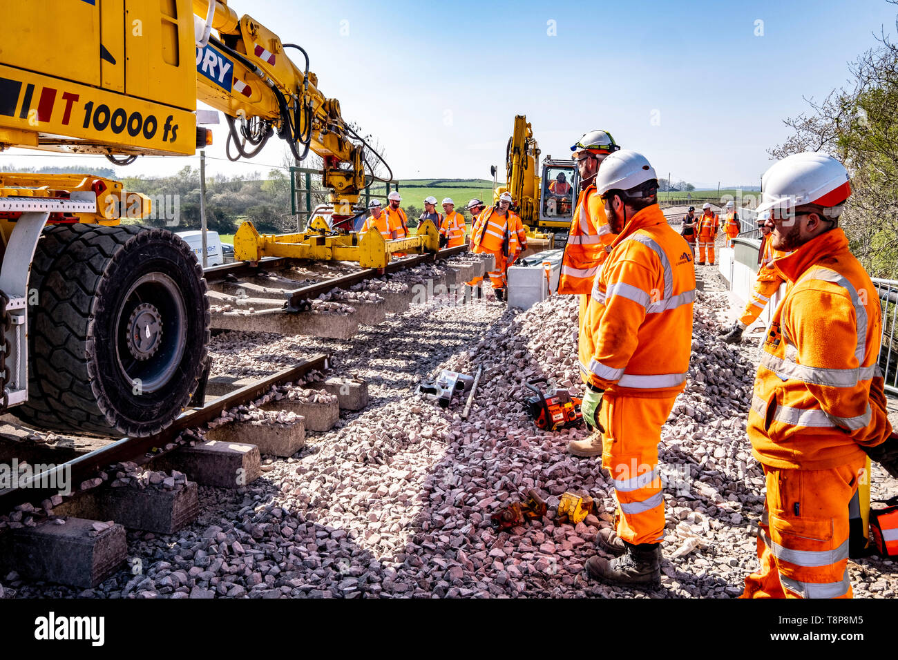 Railway workers constructing railway and lifting rail bridge into place ...