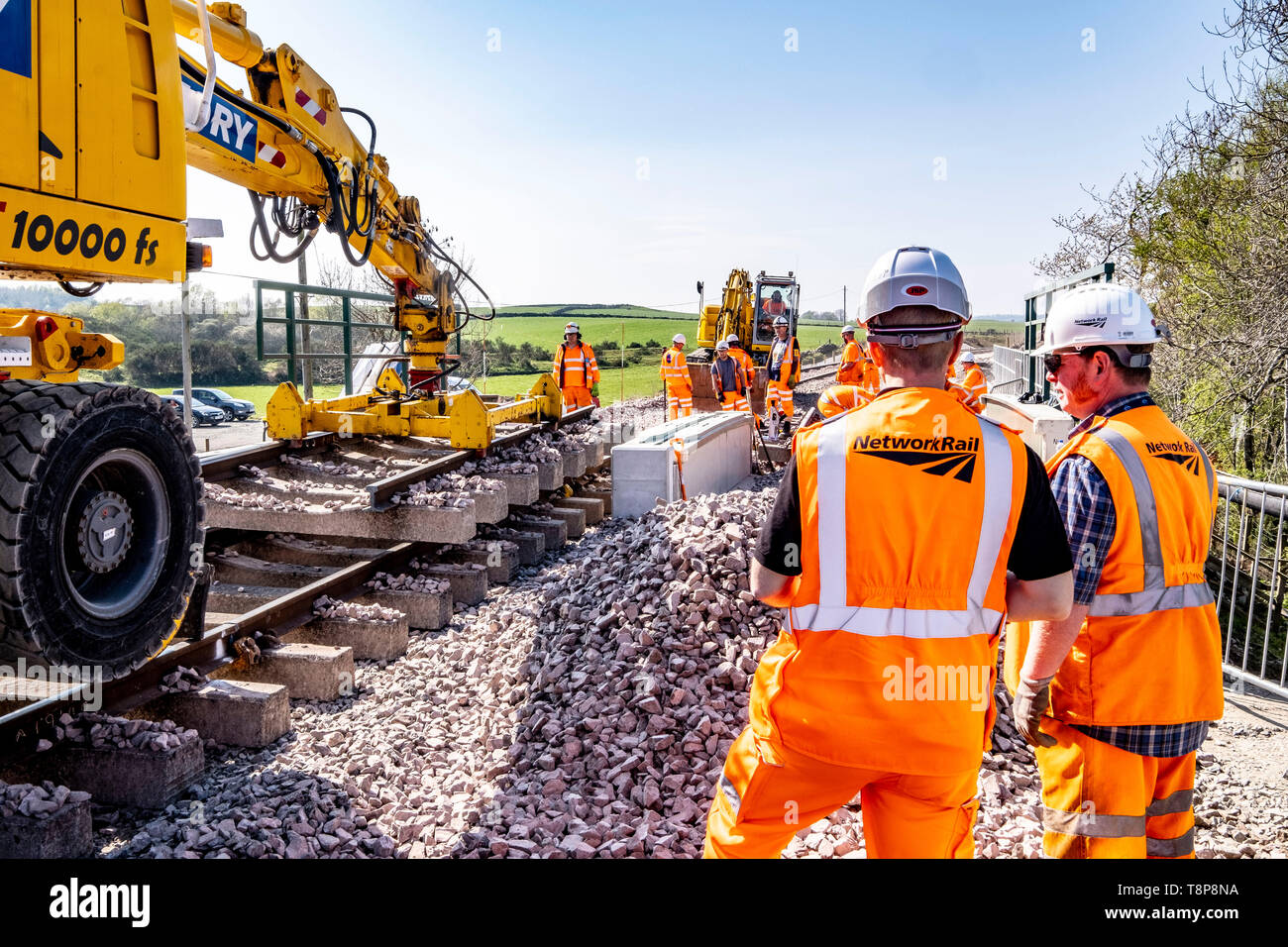 Railway workers constructing railway and lifting rail bridge into place ...