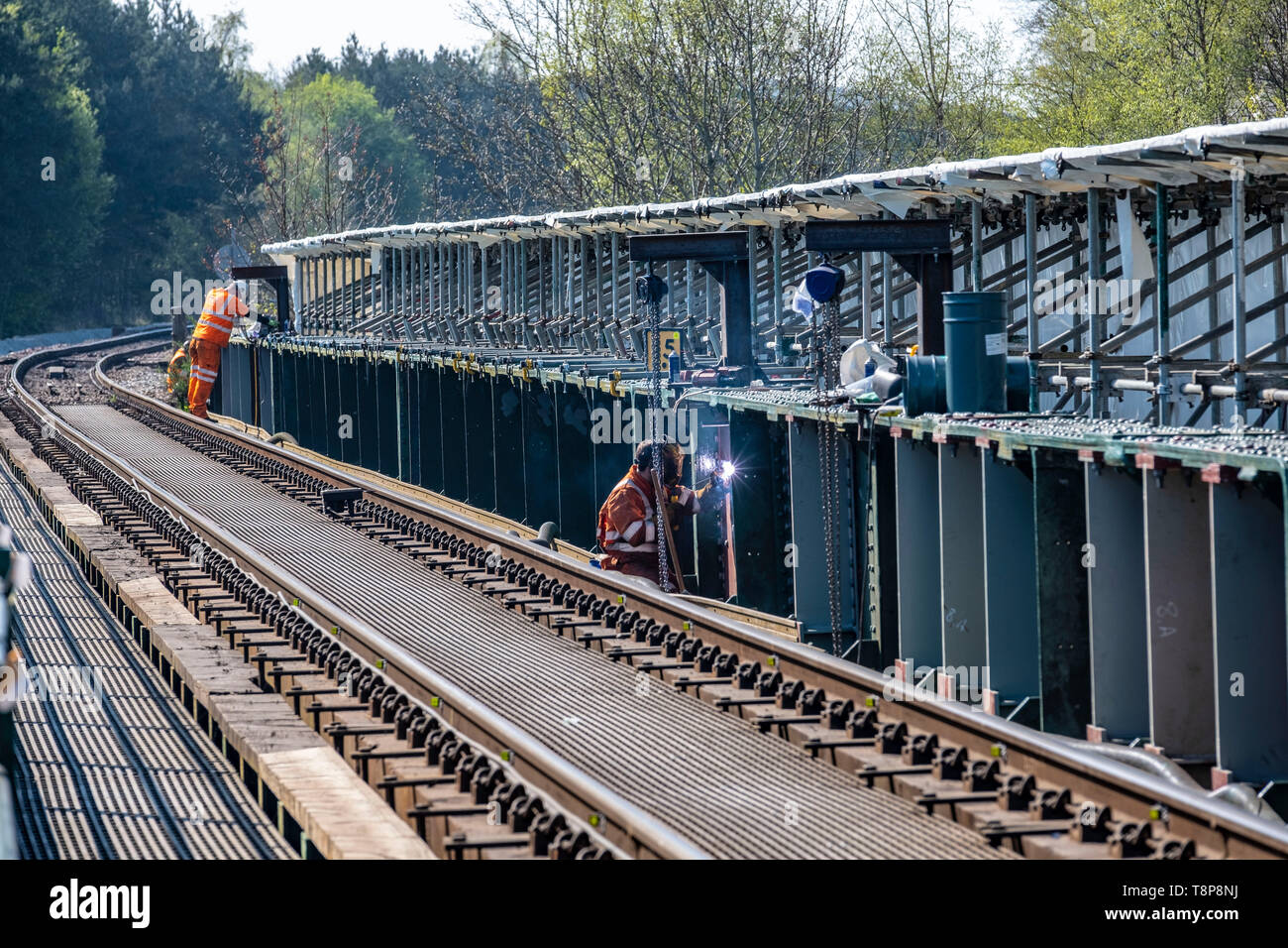 Railway workers constructing railway and lifting rail bridge into place ...