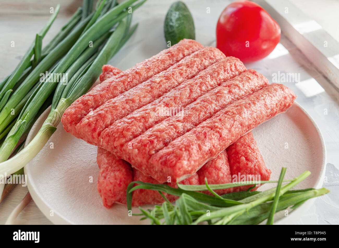 Chevapchichi is a national Balkan dish. Close up a row of fresh raw ...
