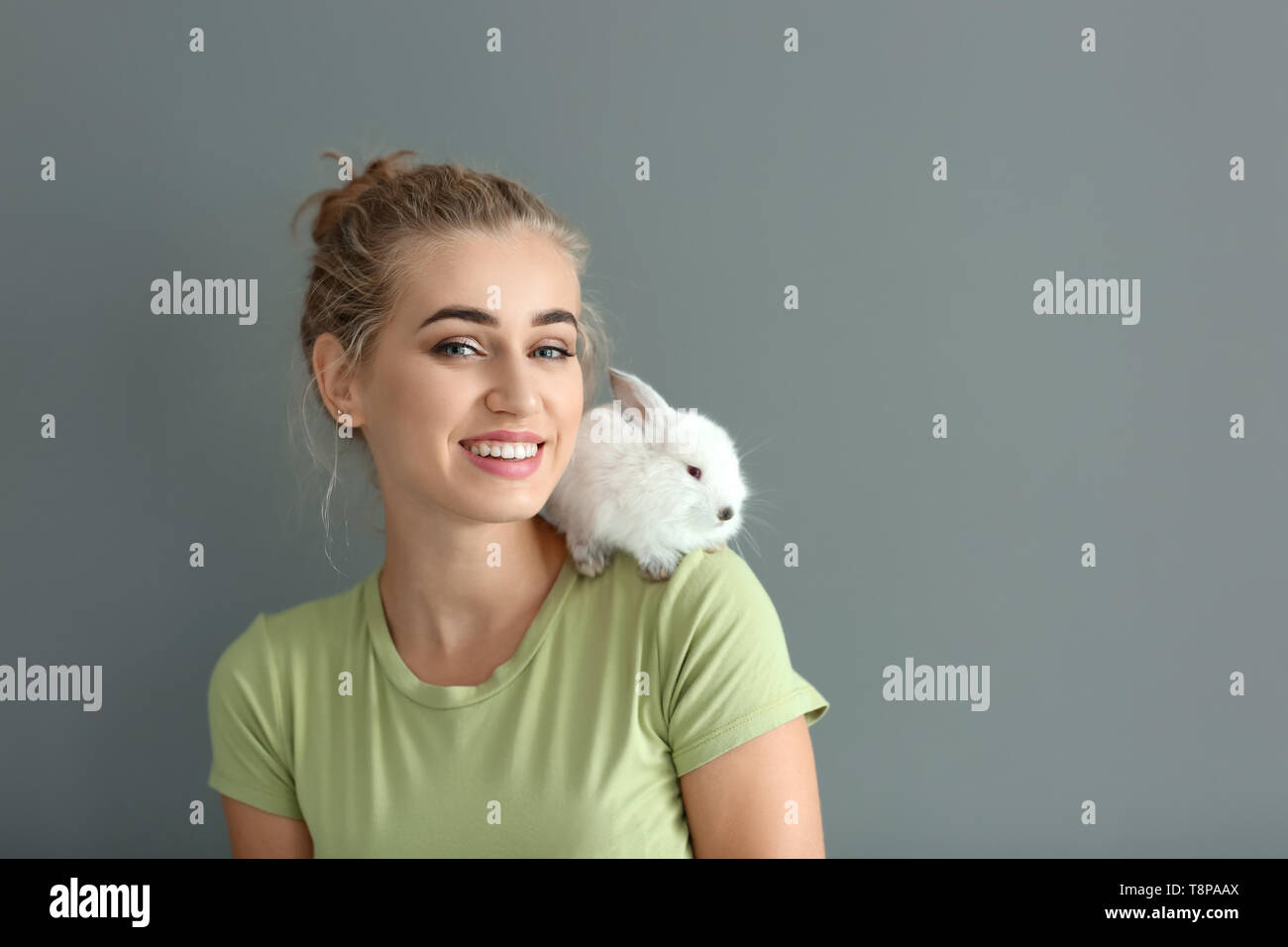 Beautiful young woman with cute rabbit on grey background Stock Photo ...