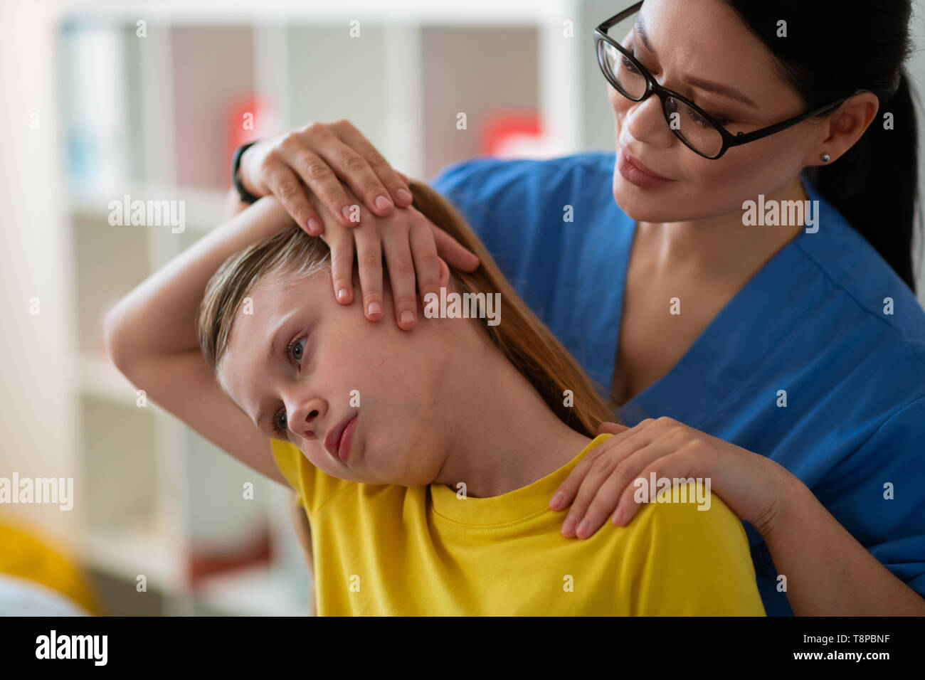 Accurate dark-haired Asian doctor stretching neck muscles Stock Photo ...