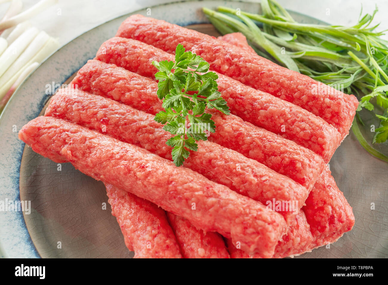 Chevapchichi is a national Balkan dish. Close up a row of fresh raw ...