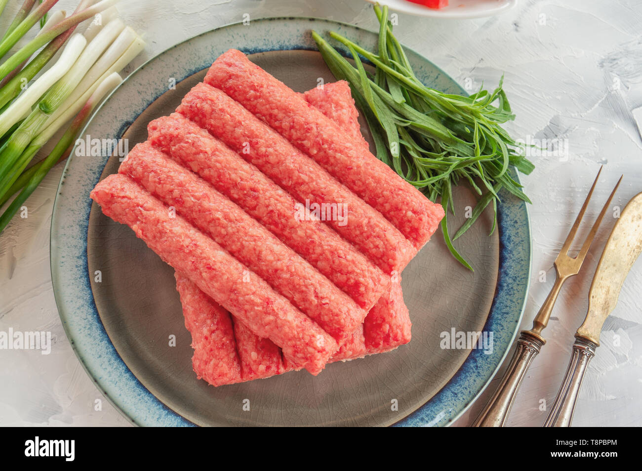 Chevapchichi is a national Balkan dish. Close up a row of fresh raw ...