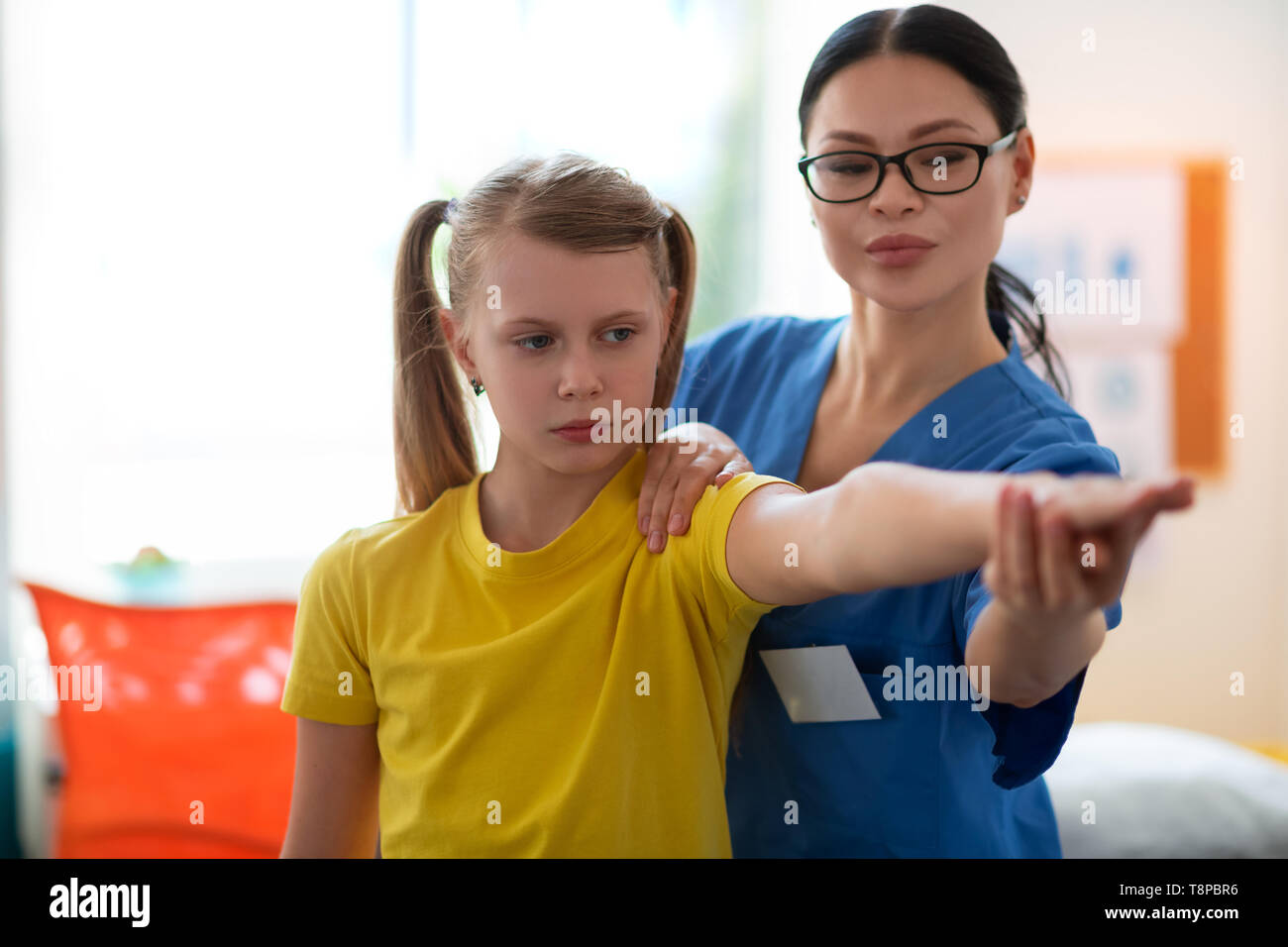 Serious long-haired girl pulling hand and showing in to curious doctor ...