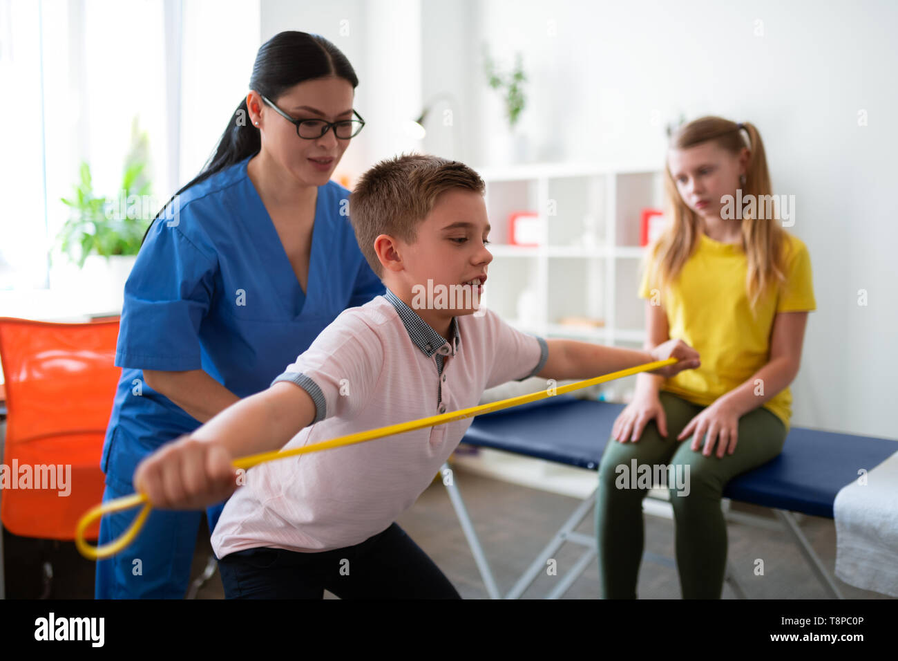 Serious young boy training with sportive rope while doctor Stock Photo ...