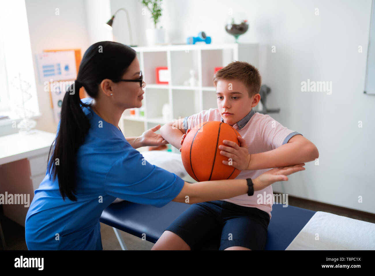 Calm hard-working boy sitting on the daybed and pushing hands into ...