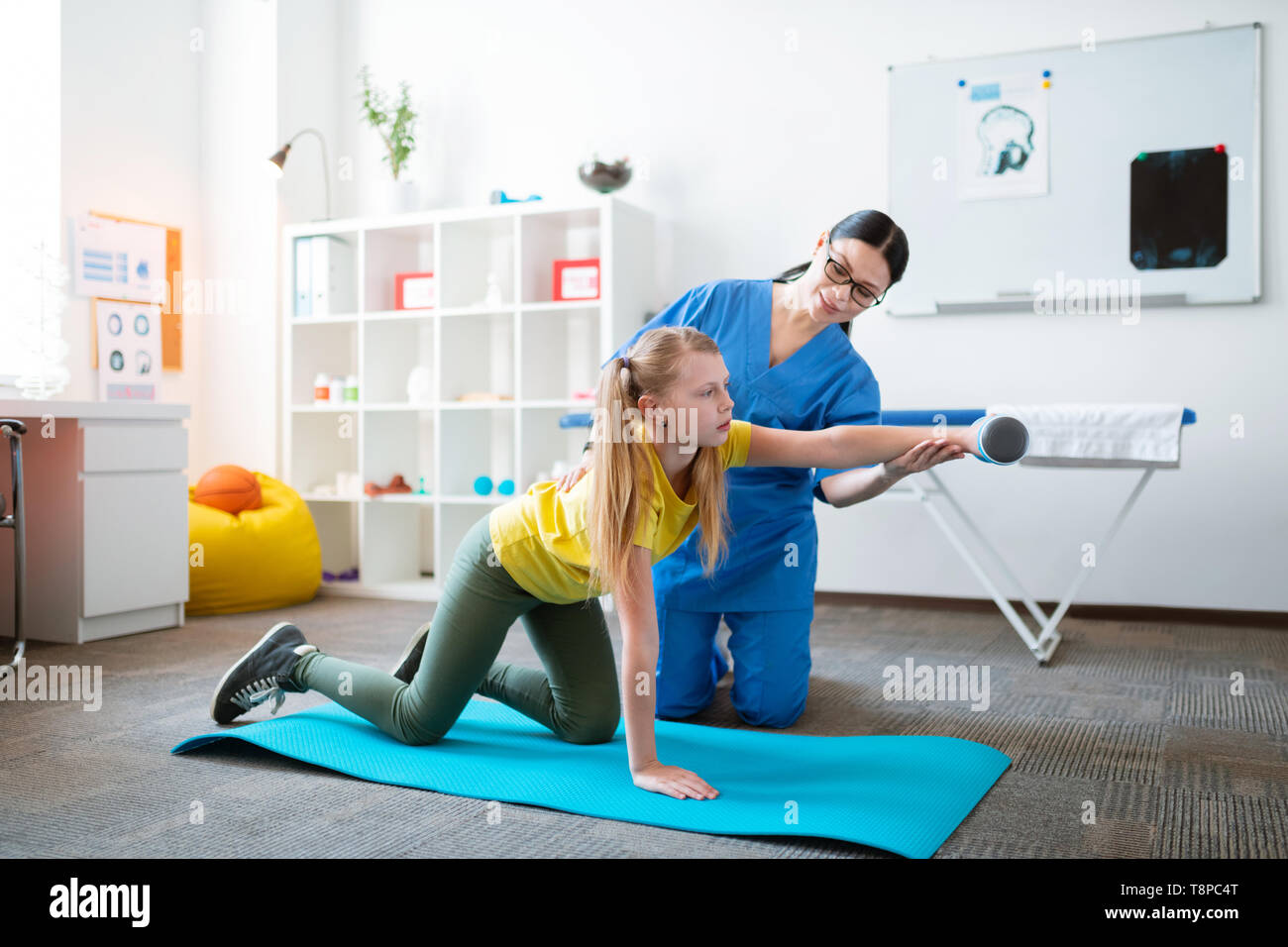 Smiling peaceful Asian doctor sitting on the floor and assisting Stock ...