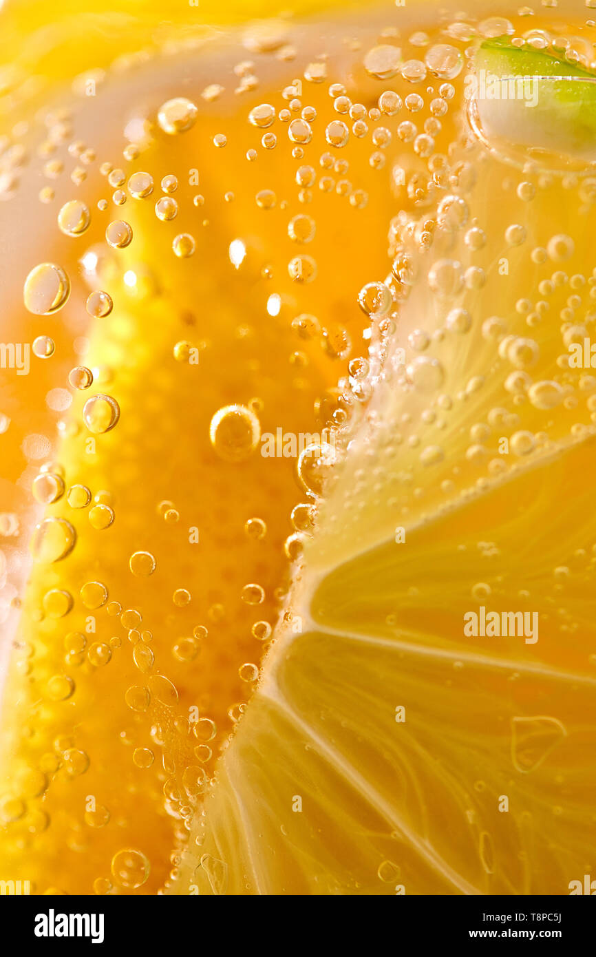 Macro photo of yellow lemon slices with lots of bubbles in a glass with ...