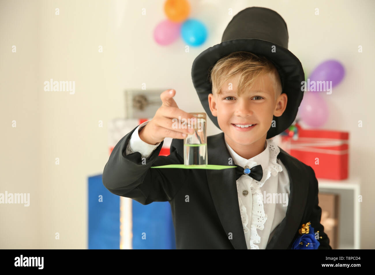 Cute little magician showing trick indoors Stock Photo - Alamy