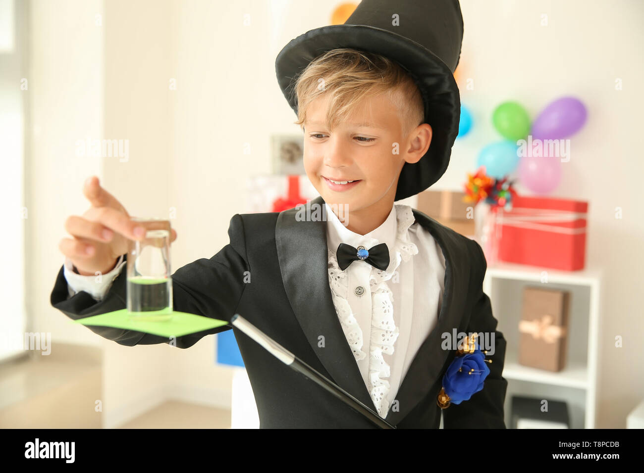 Cute little magician showing trick indoors Stock Photo - Alamy