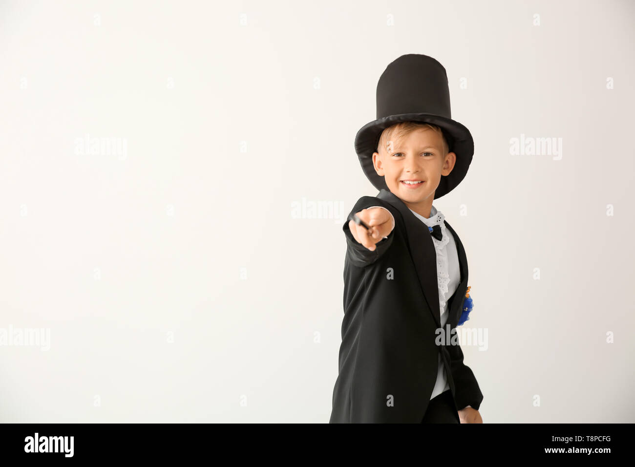 Cute little magician showing tricks on white background Stock Photo - Alamy