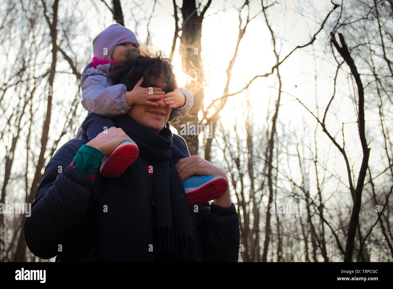 Young dad carrying baby on his shoulders in a forest at sunset. Baby ...