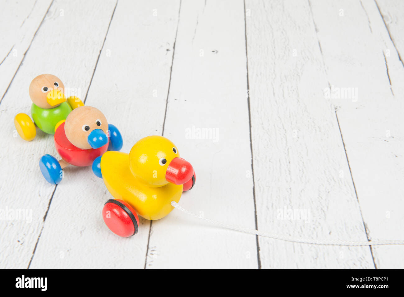 Wooden duck pull kids toy with a string on a white wooden background ...