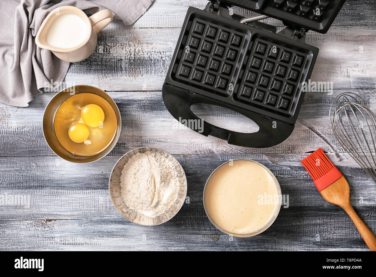 Modern waffle maker with ingredients on wooden table Stock Photo - Alamy